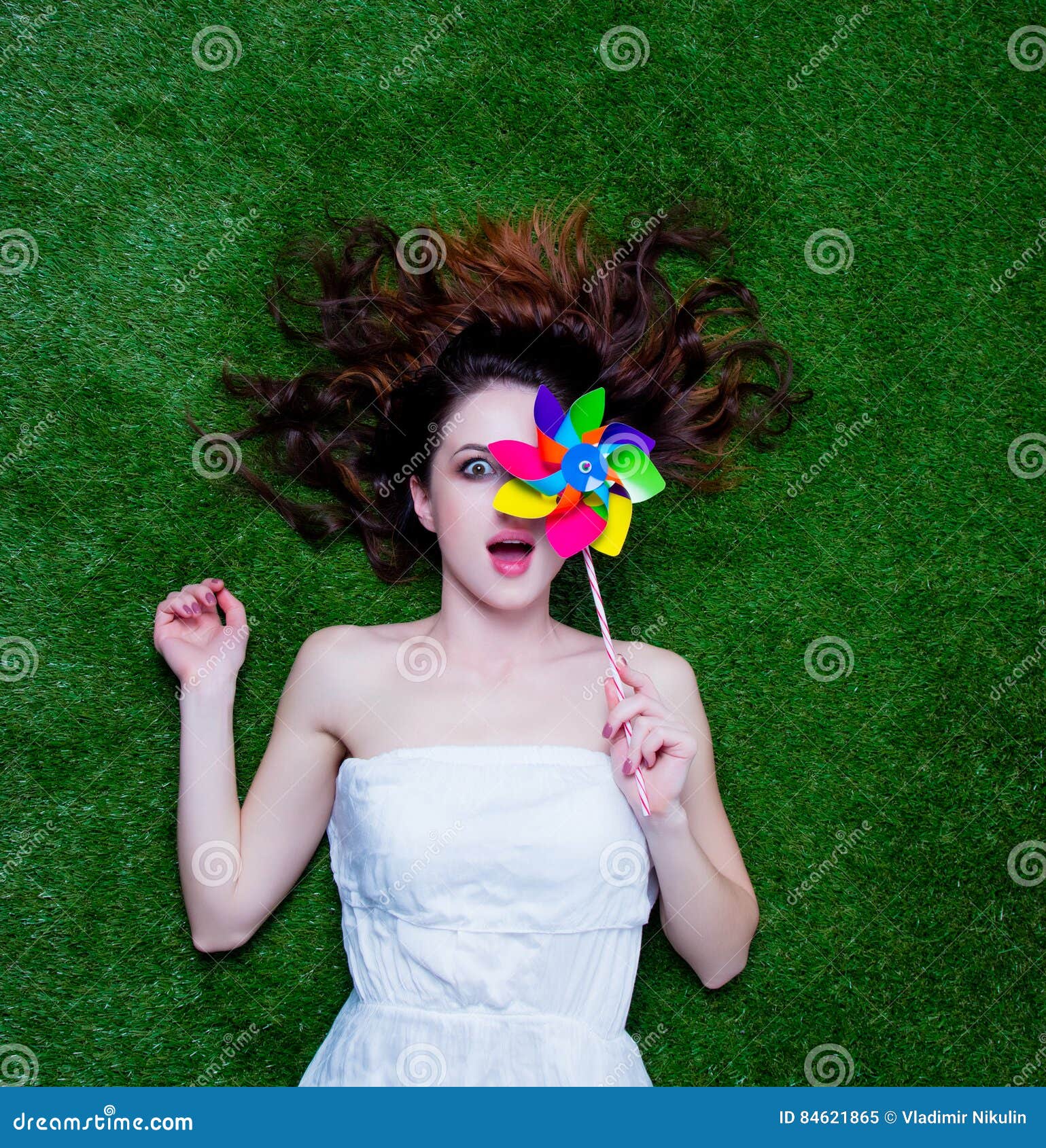 Portrait Of A Young Redhead Woman With Pinwheel Lying Down On Gr Stock