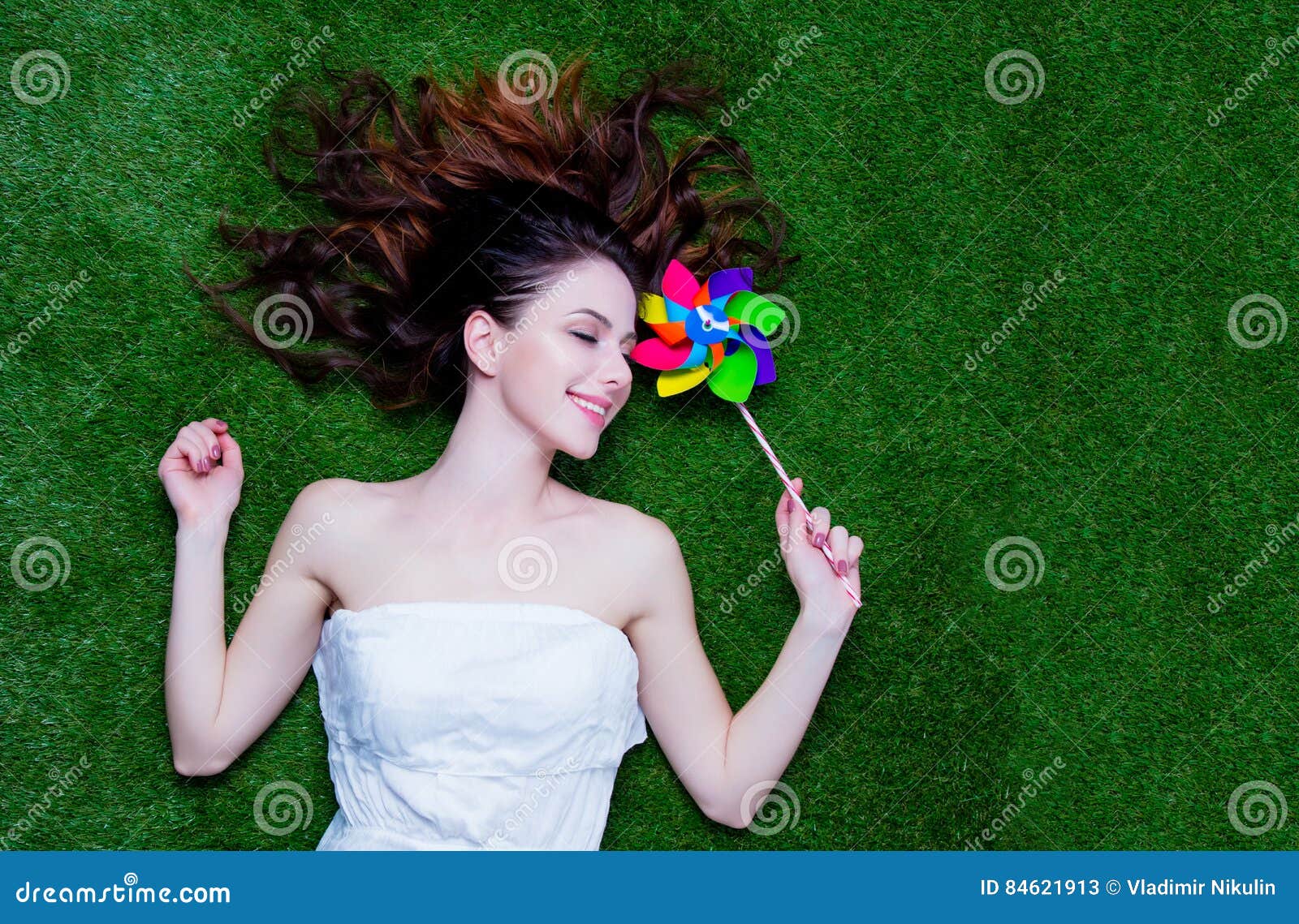 Portrait Of A Young Redhead Woman With Pinwheel Lying Down On Gr Stock