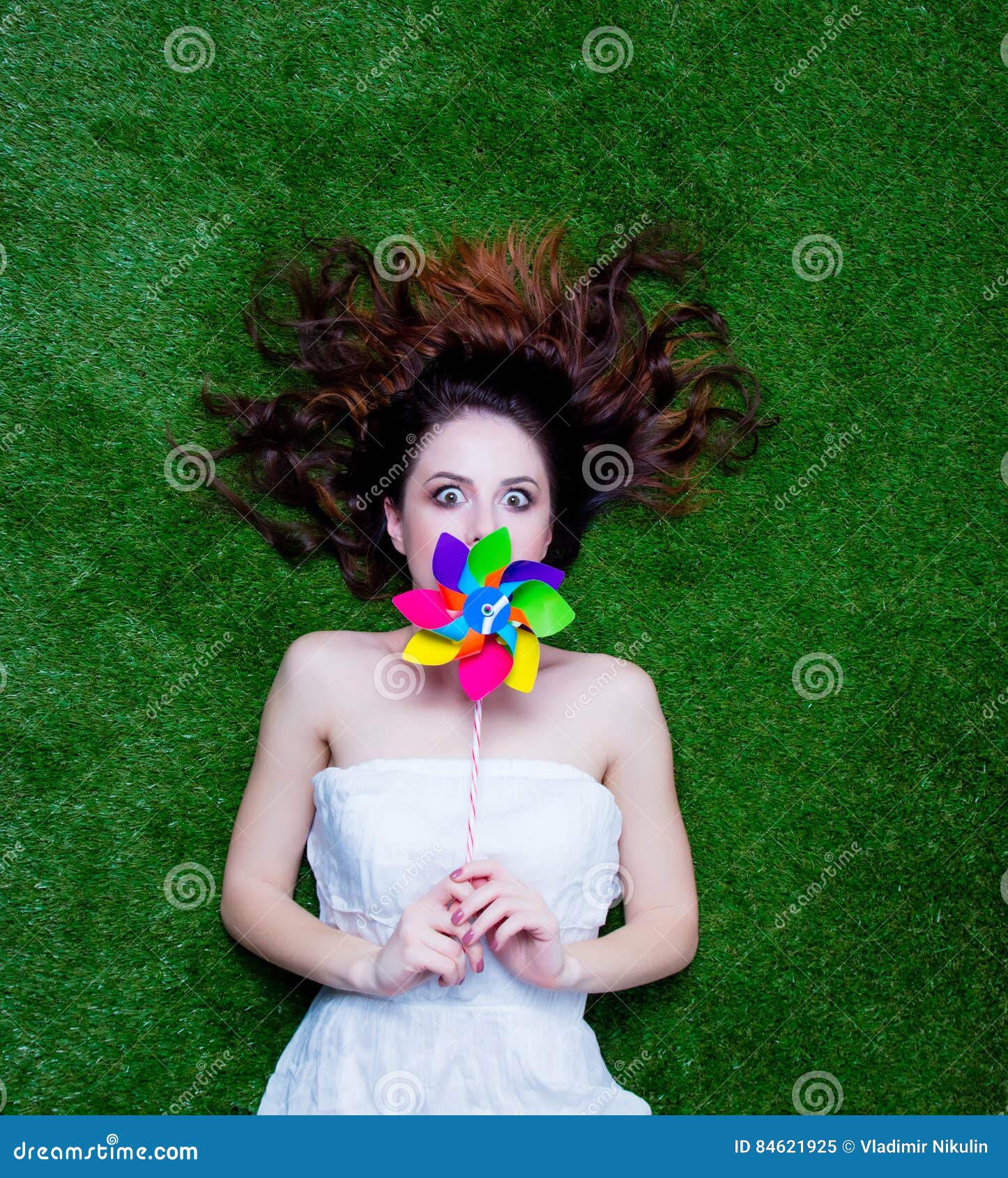 Portrait Of A Young Redhead Woman With Pinwheel Lying Down On Gr Stock