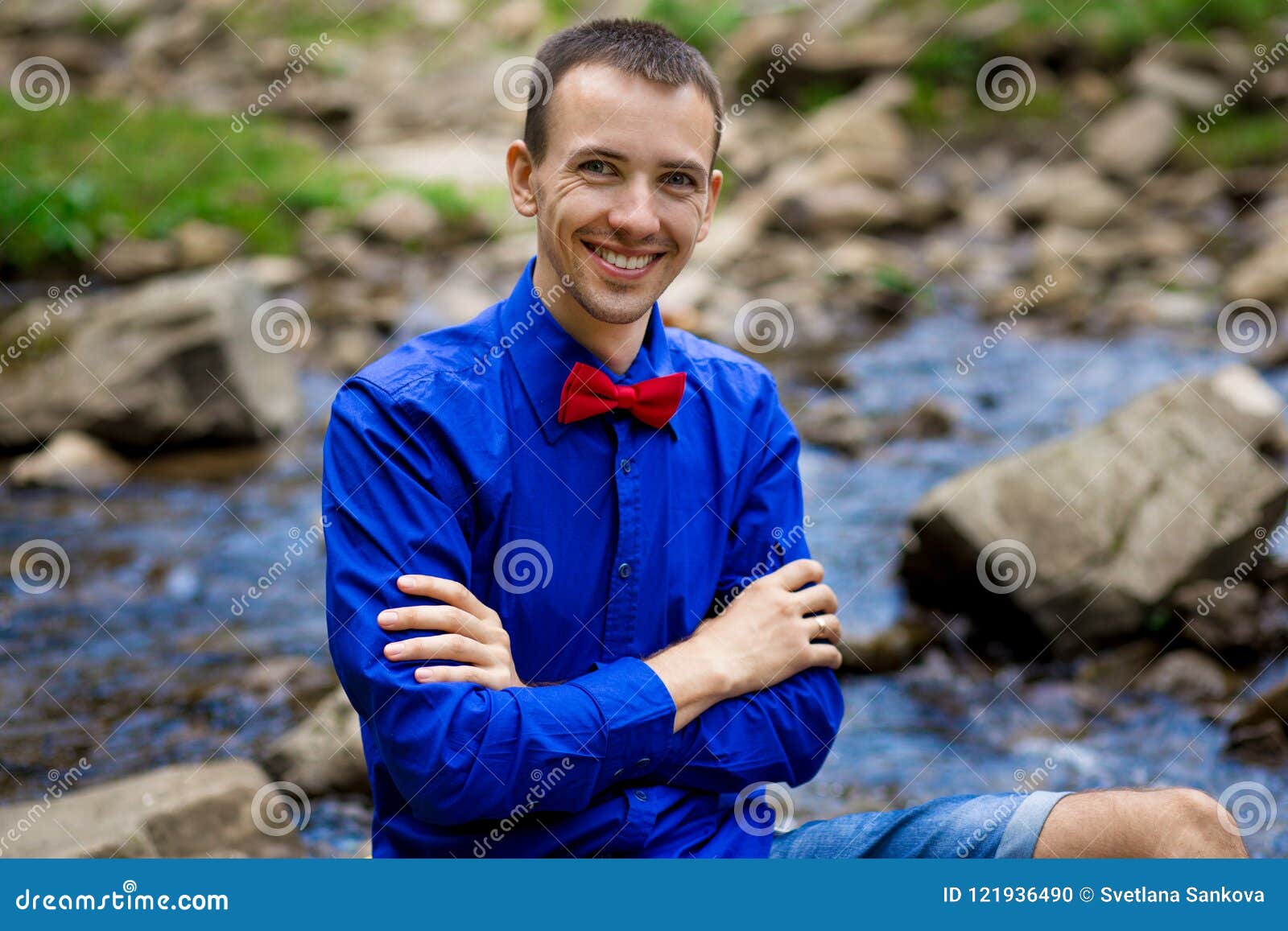 Portrait of Young Smiling Handsome Man in Blue Shirt Near Forest River ... Portrait of Young Smiling Handsome Man in Blue Shirt Near Forest River ...