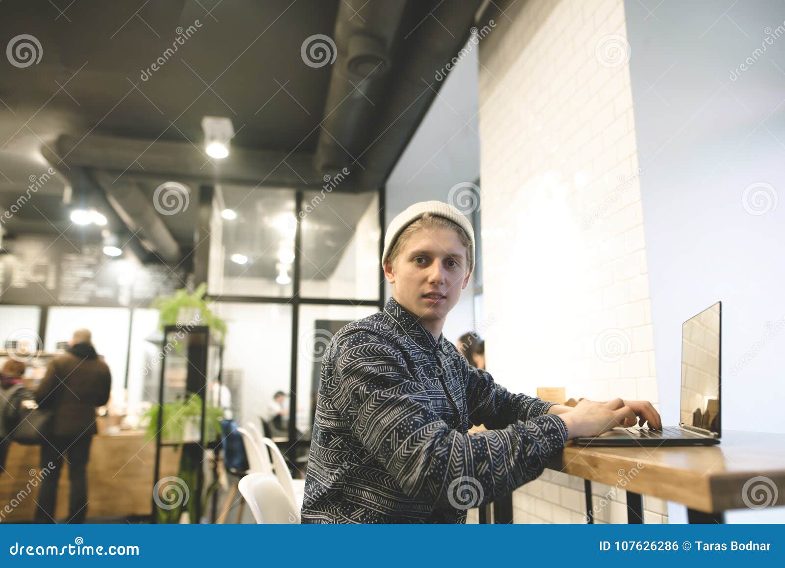 Portrait of a Young Student Sitting at a Cafe at the Table and Using a ...