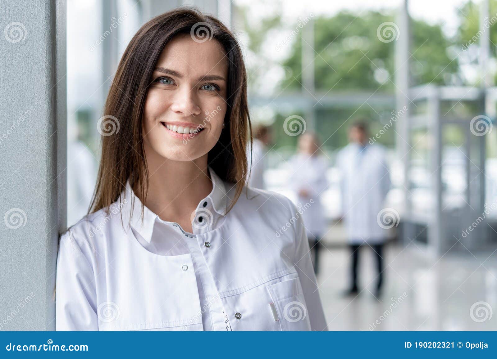 Portrait Of Young Woman Doctor With White Coat Standing In Hospital