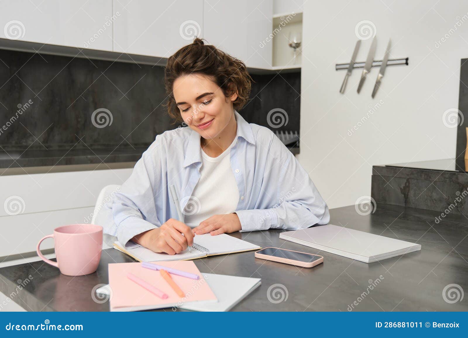 Portrait of Young Woman Working from Home, Writing Down Information in ...