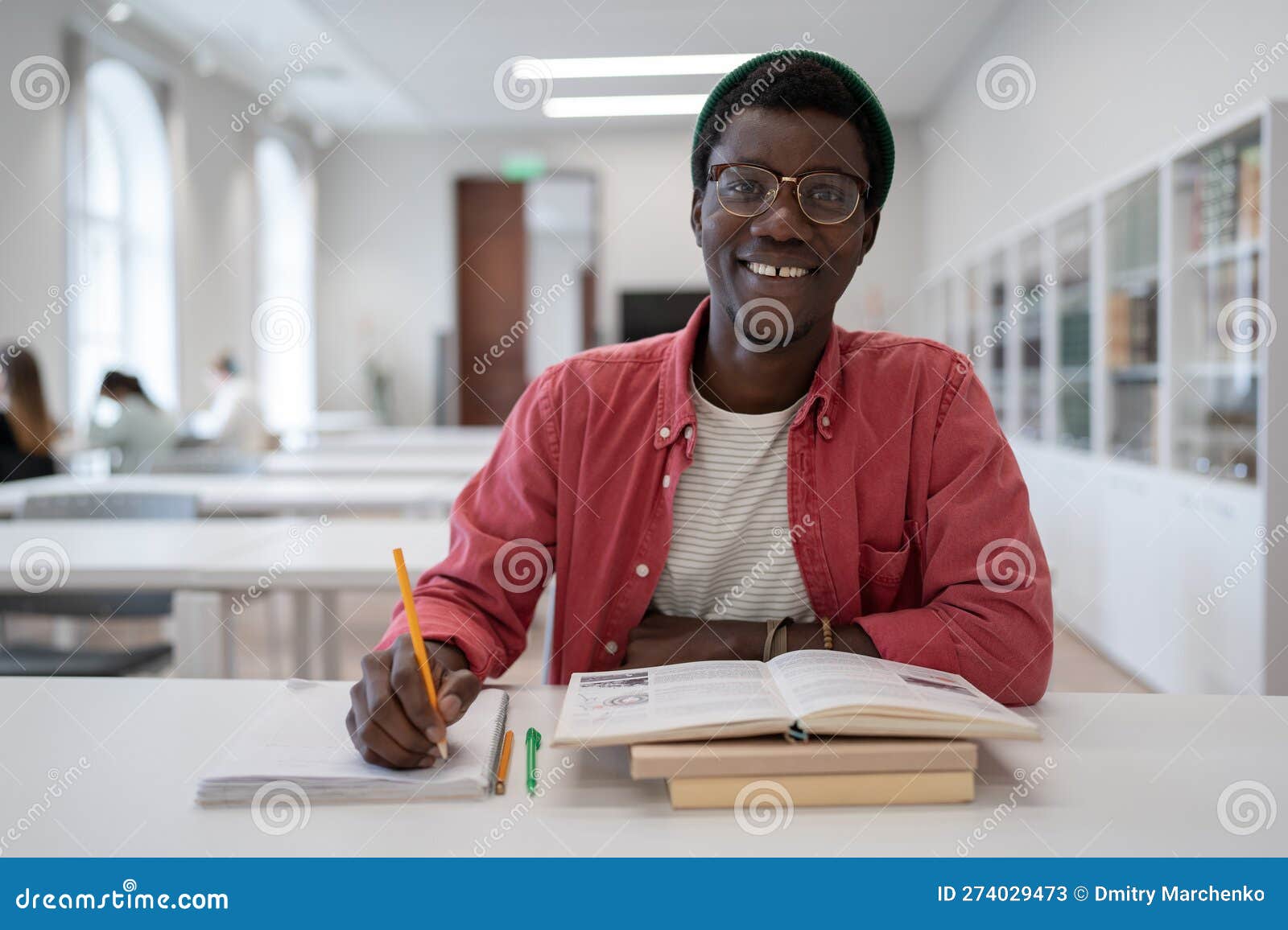 African American Young Man Studying in University Library Making Notes ...