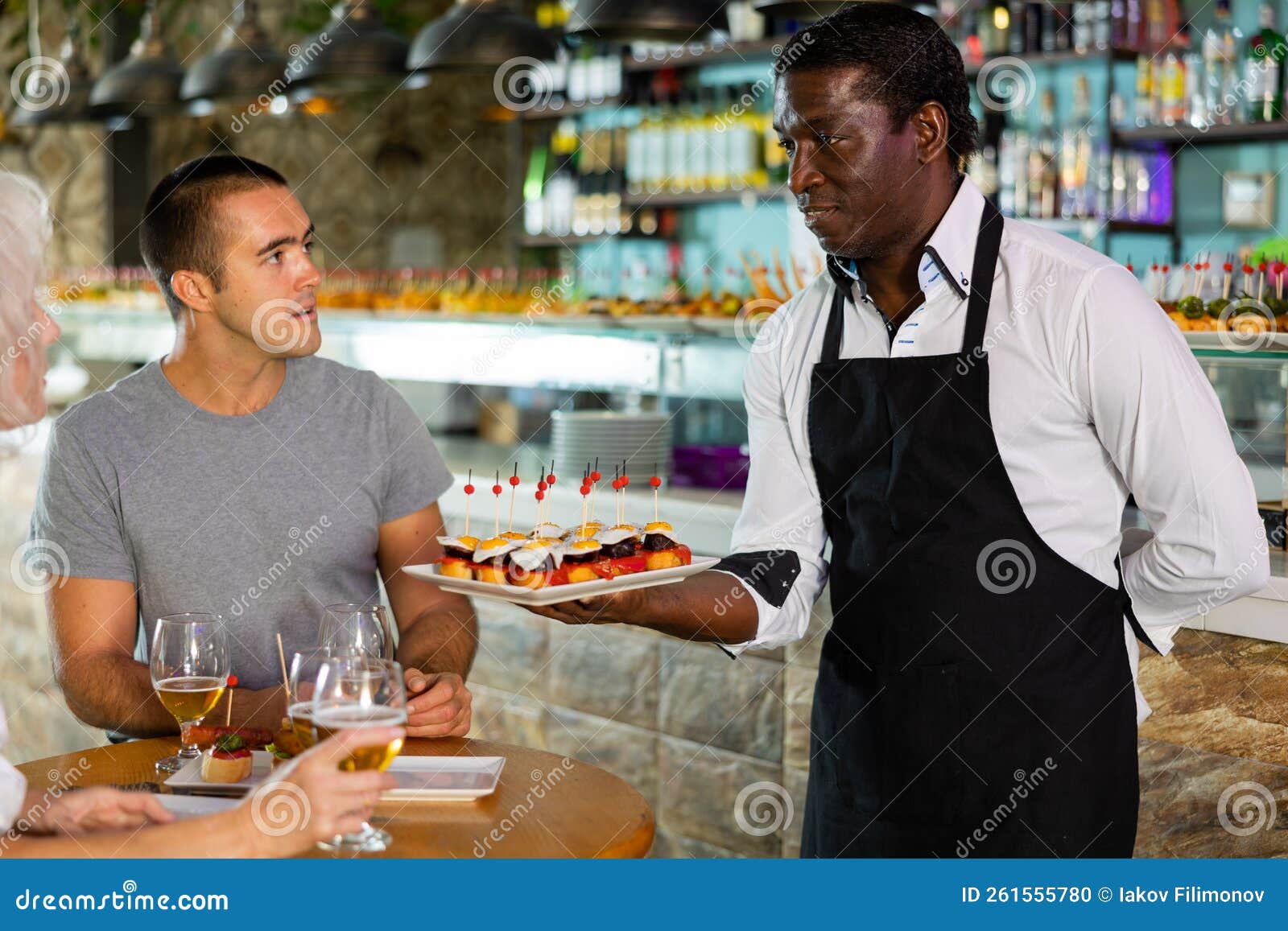 Happy African American Waiter Standing With Plates Of Pinchos In The