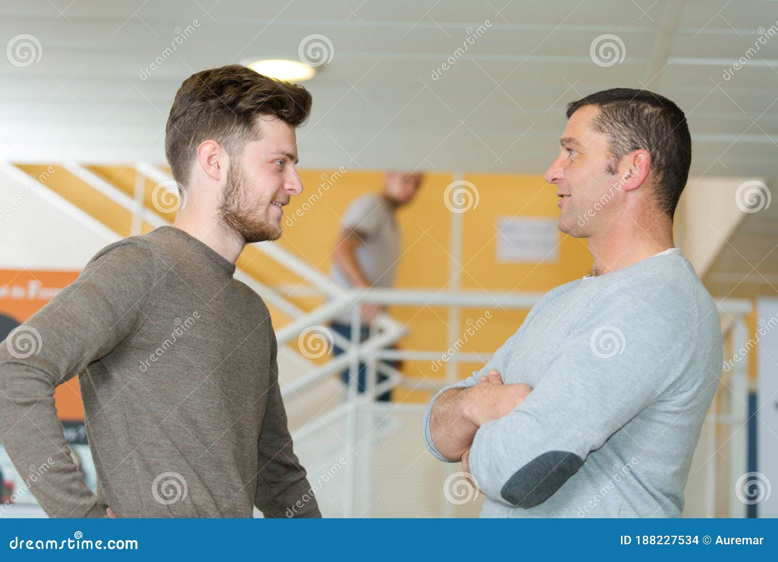 Positive Men Talking in Corridor Stock Photo - Image of listening ...