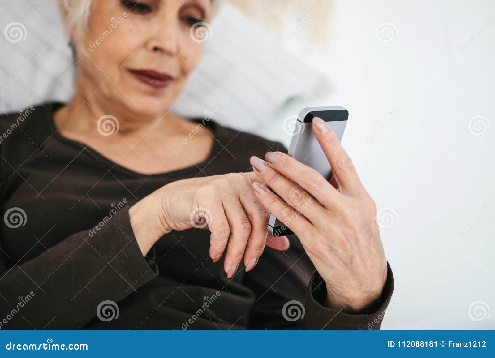 A Positive Modern Elderly Woman Is Holding A Cell Phone And Is Using It ...