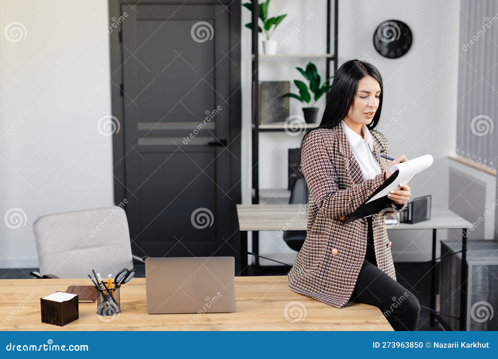 Positive Woman Sitting at Office Table Writing Notes on Paper while ...