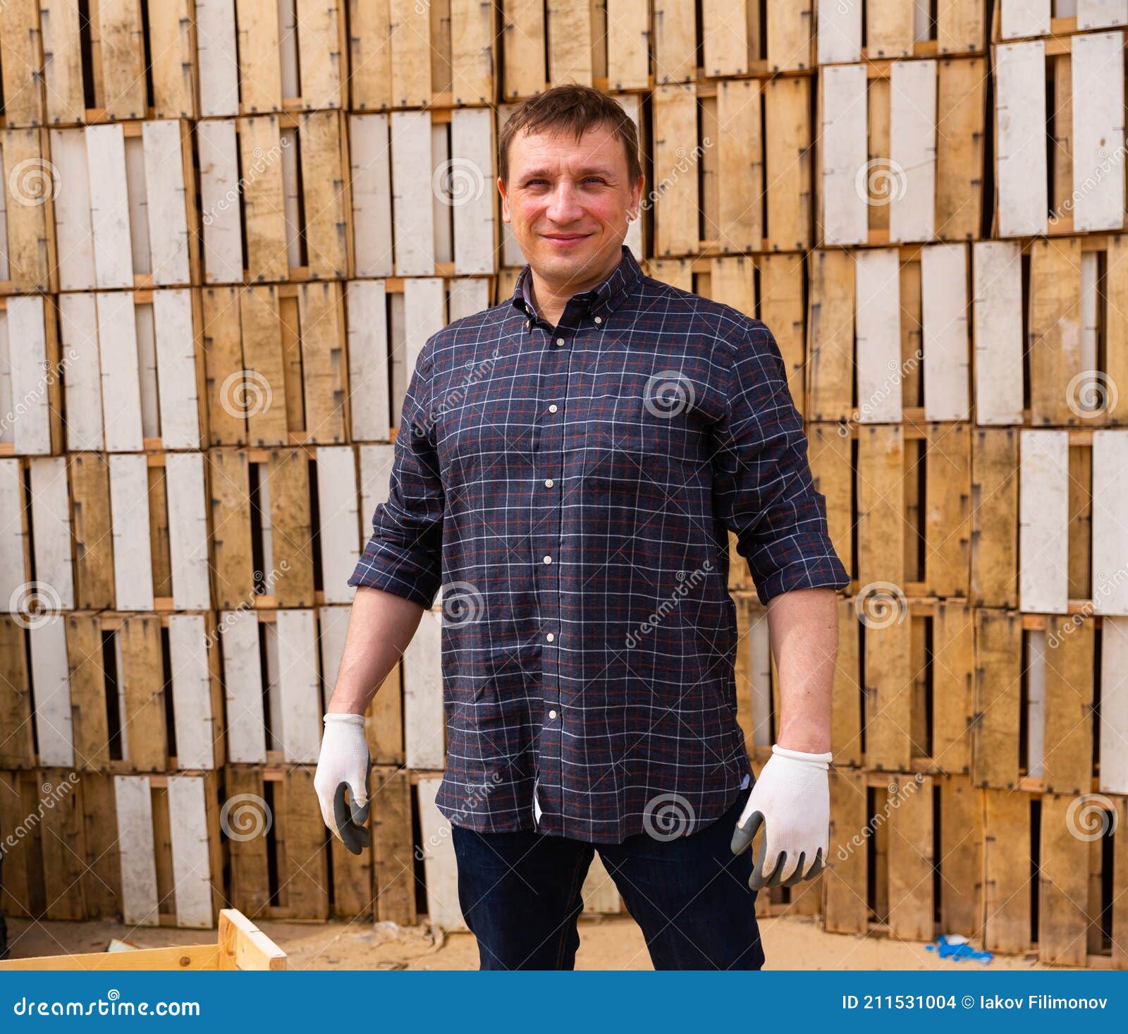 Positive Worker Standing Against the Background of Wooden Boxes Stock ...