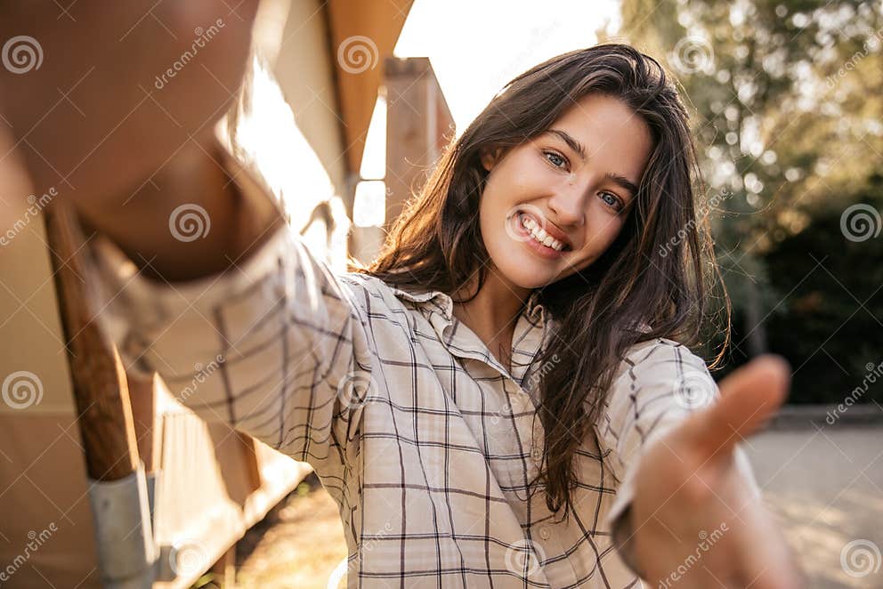 Positive Young Caucasian Woman Stretches Hands To Camera Walking In