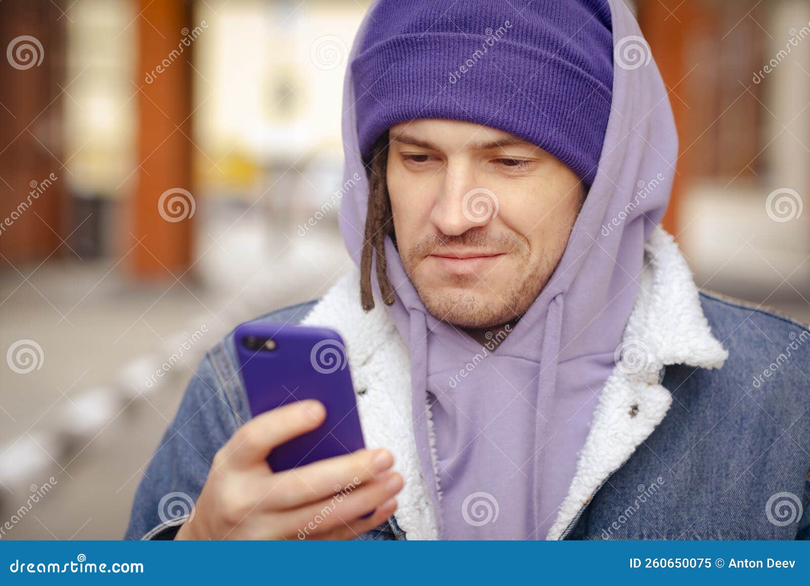 Positive Young Male in Warm Clothes Smiling and Browsing Mobile Phone ... Positive Young Male in Warm Clothes Smiling and Browsing Mobile Phone ...