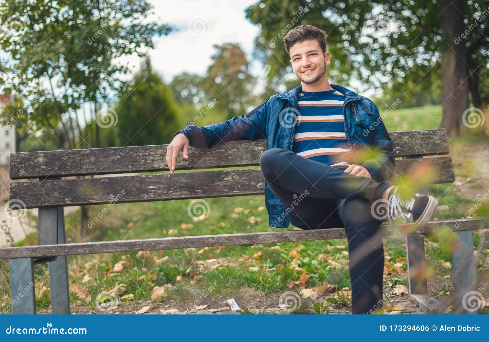Positive Young Man with Smile on His Face Sitting on Bench Stock Photo ...