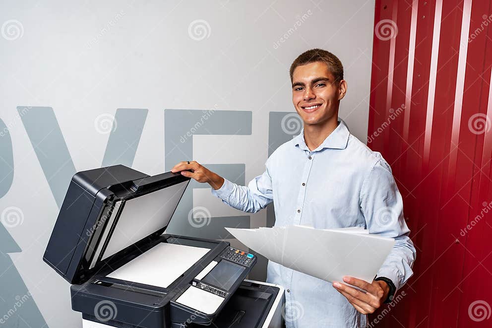 Positive Young Man Using Printer in the Modern Office Stock Photo ...