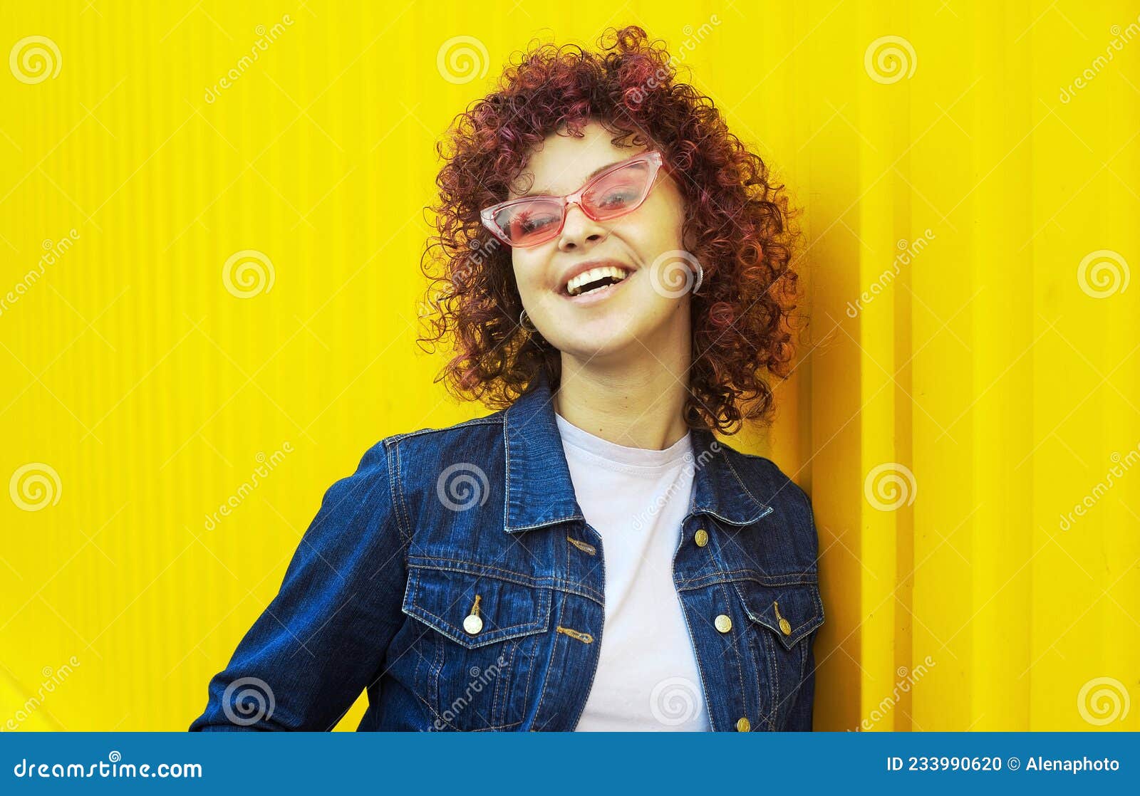 Happy Curly Haired Woman In Denim Clothes On Yellow Background Stock