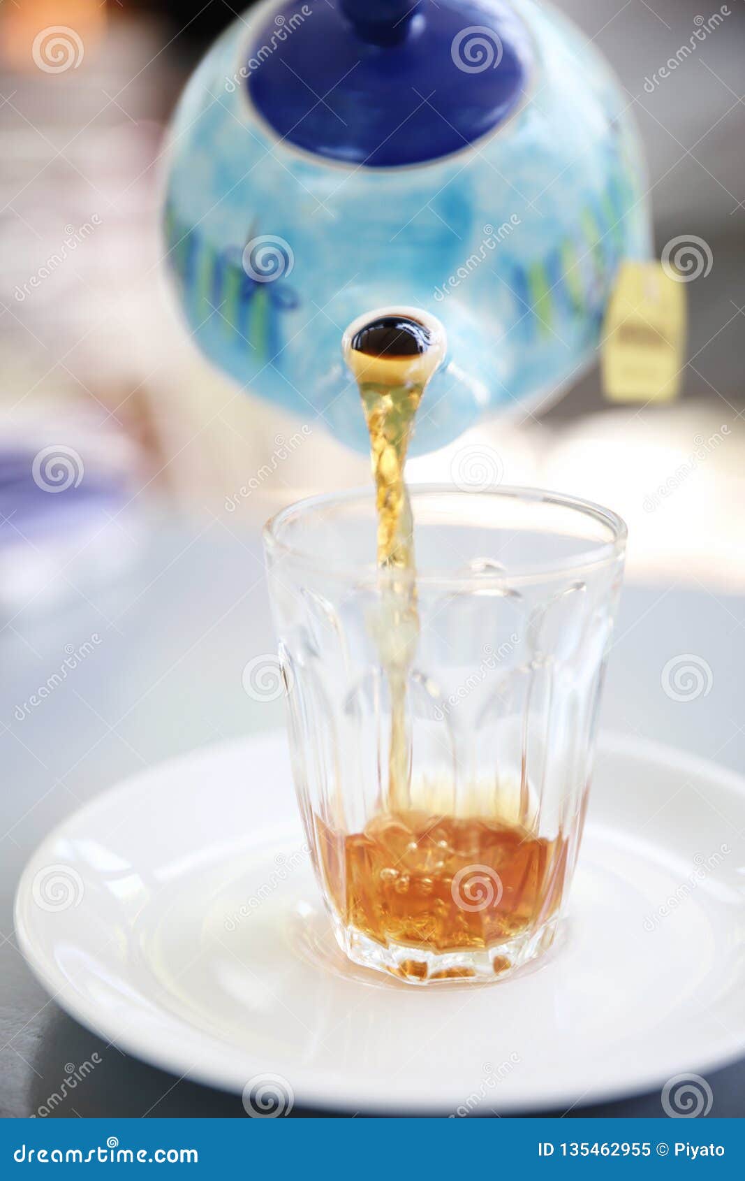 Pour tea pot on tea cup stock image. Image of glass - 135462955