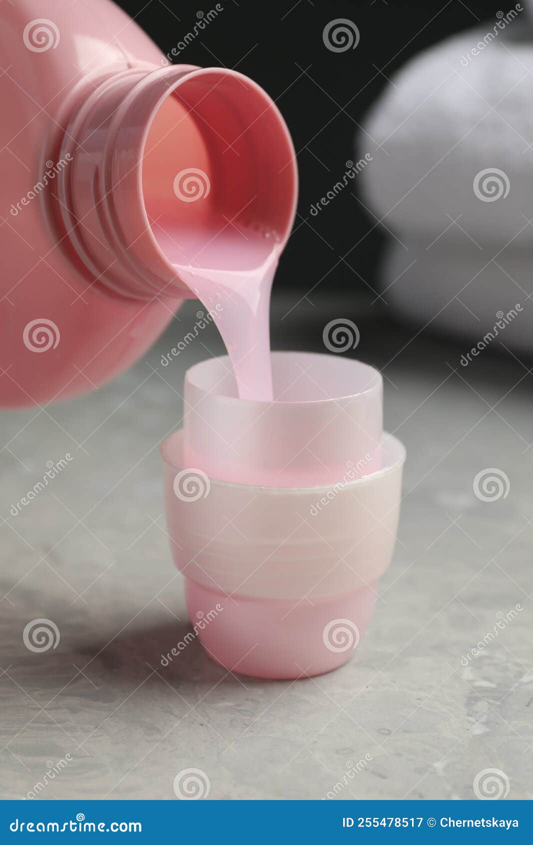 Pouring Laundry Detergent from Bottle into Cap on Light Grey Marble ...