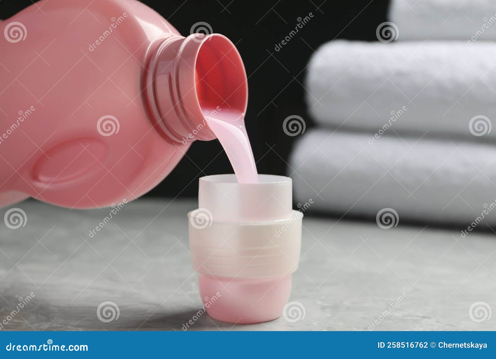 Pouring Laundry Detergent from Bottle into Cap on Light Grey Marble ...