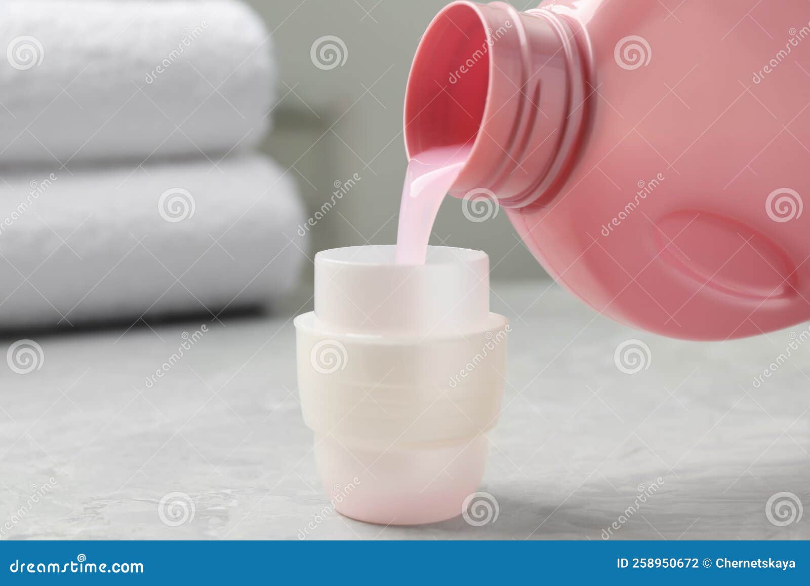 Pouring Laundry Detergent from Bottle into Cap on Light Grey Marble ...