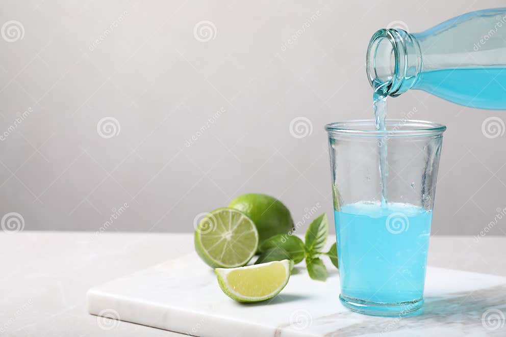 Pouring Refreshing Light Blue Drink into Glass on White Table, Space ...
