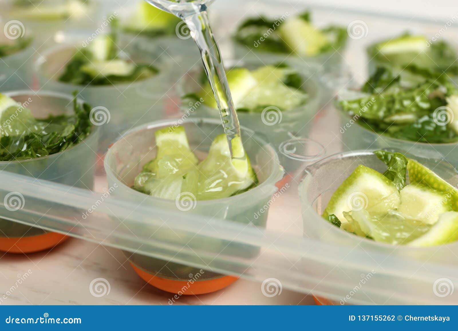 Pouring Water into Ice Cube Tray with Lime Slices and Mint Stock Photo ...