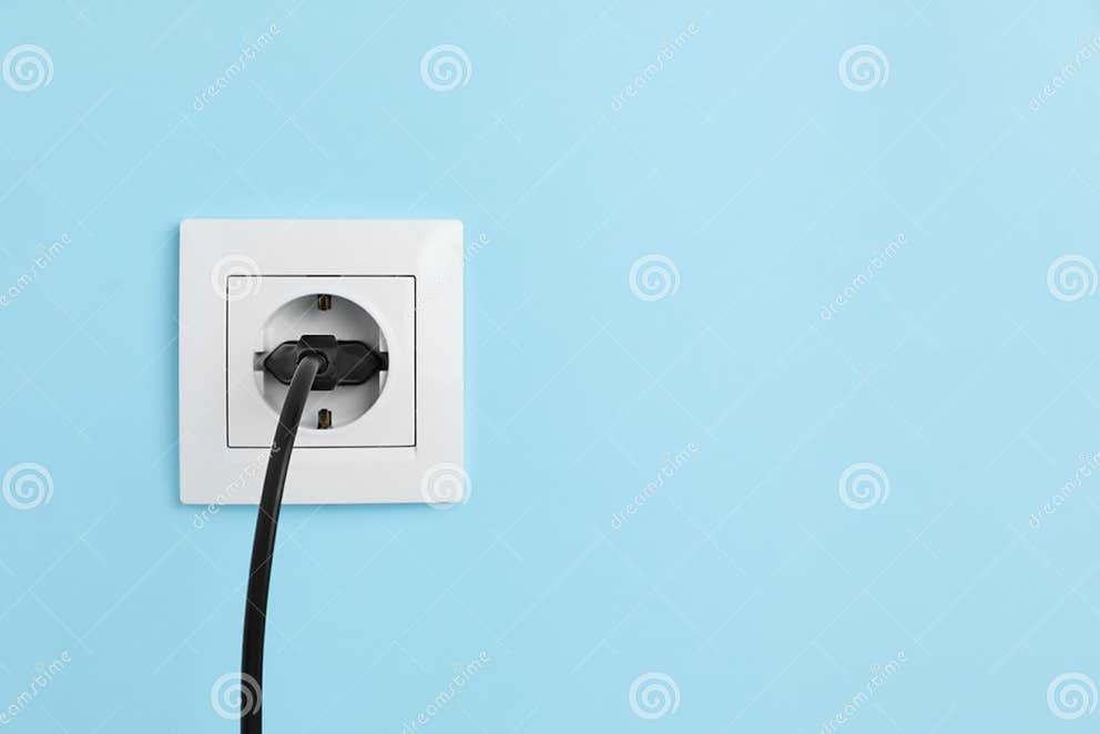 Power Socket with Inserted Plug on Light Blue Wall, Space for Text ...