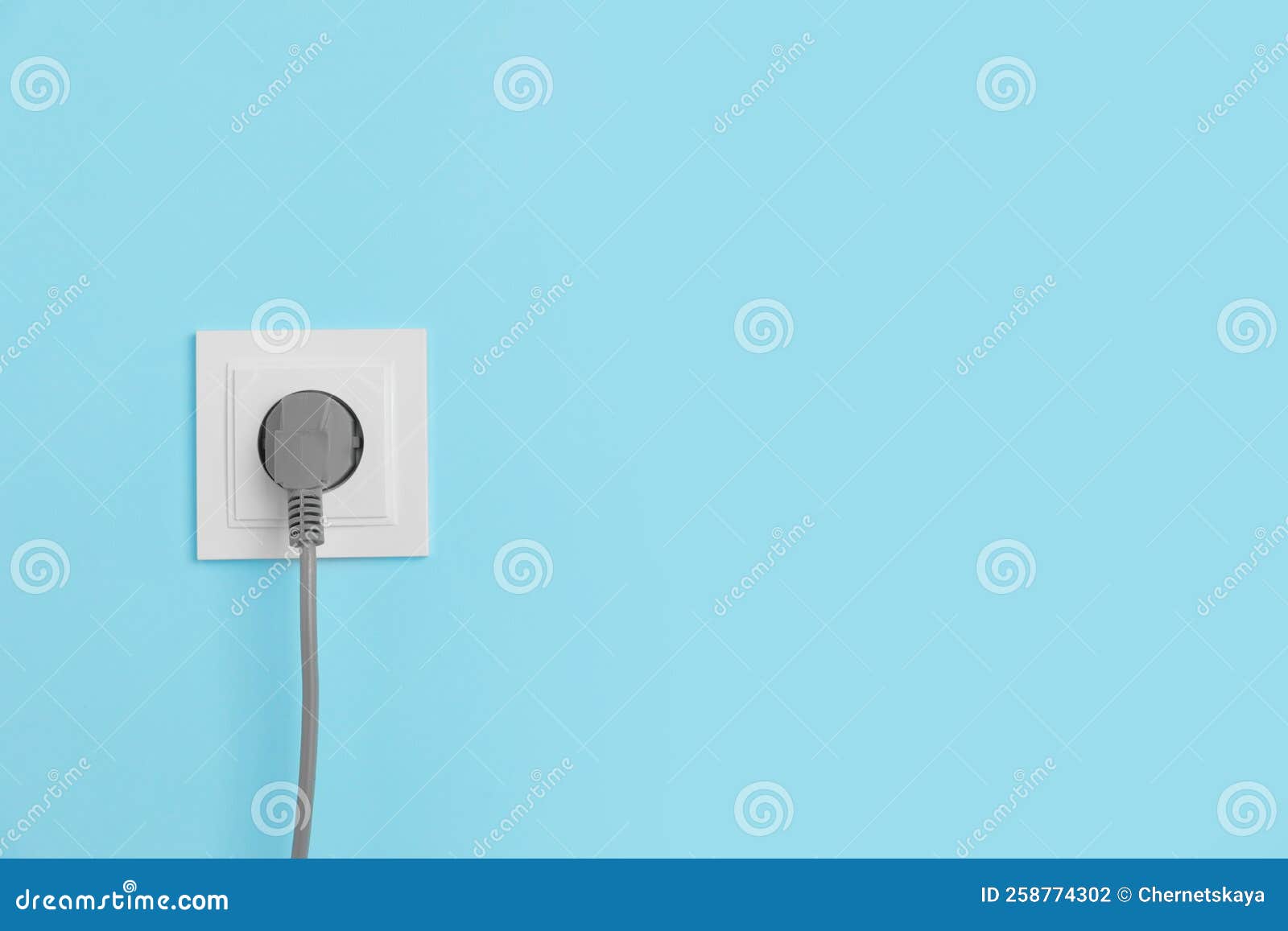 Power Socket with Inserted Plug on Light Blue Wall, Space for Text ...