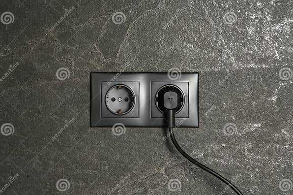 Power Sockets with Inserted Plug on Dark Grey Wall. Electrical Supply ...