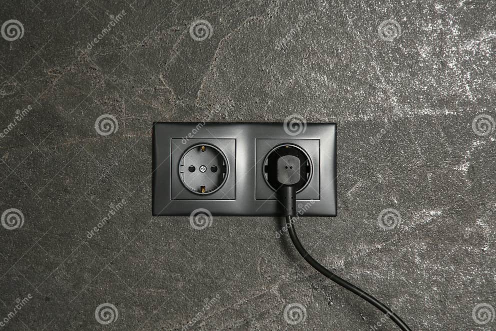 Power Sockets with Inserted Plug on Dark Grey Wall. Electrical Supply ...