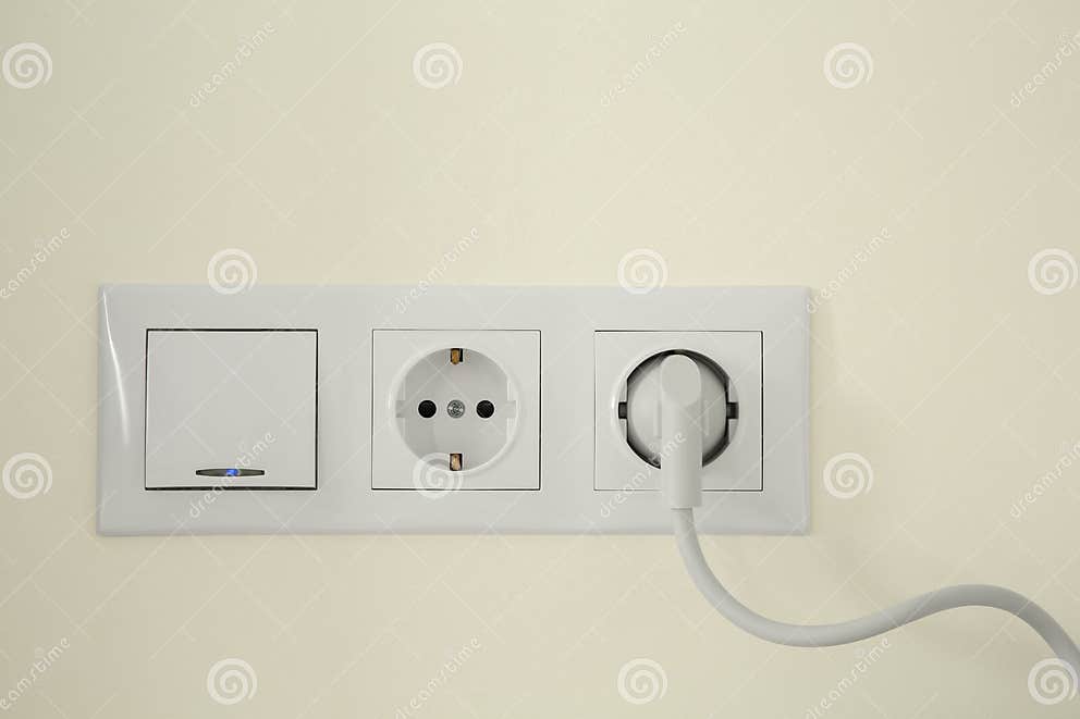 Power Sockets with Inserted Plug and Light Switch on White Wall Indoors ...