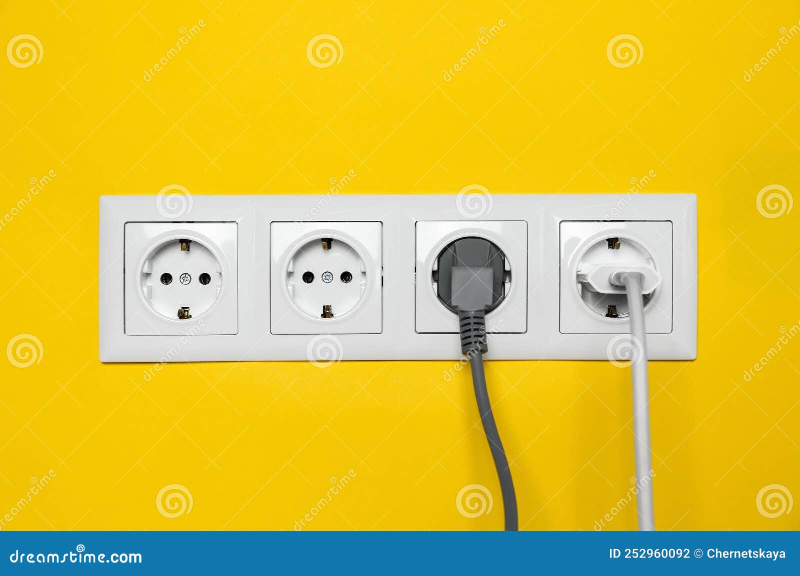 Power Sockets with Inserted Plugs on Yellow Wall. Electrical Supply ...