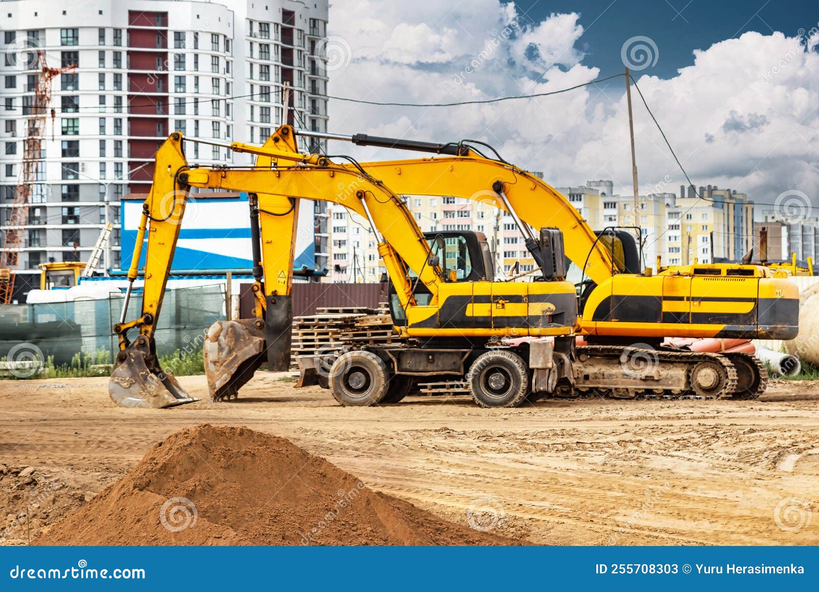 Powerful Excavators at a Construction Site Against a Blue Cloudy Sky ...