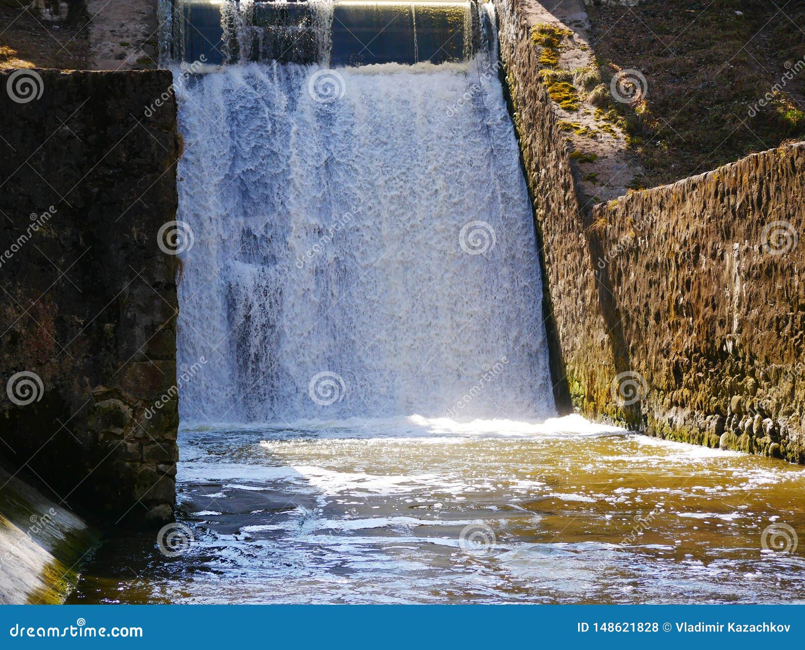 A Powerful Stream of Water Flows through the Stone Dam. Sunny Day ...