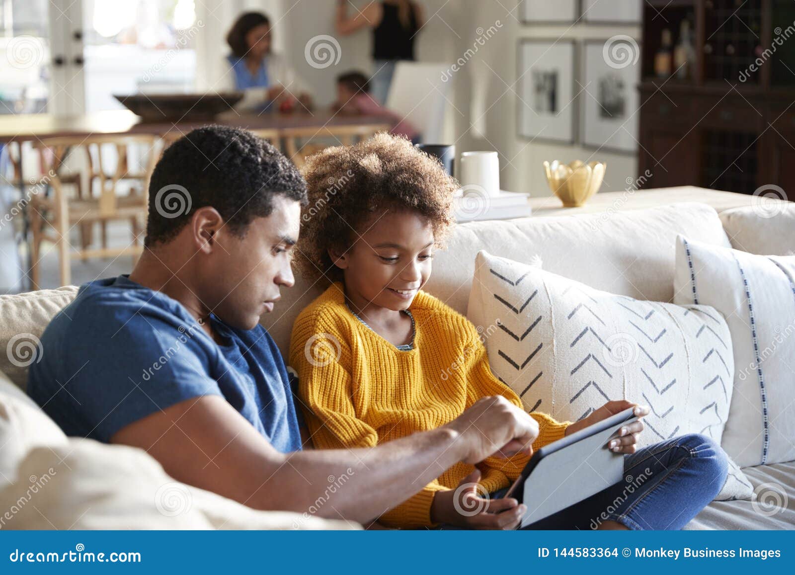 Pre Teen Girl Sitting On Sofa In The Living Room Using Tablet Computer