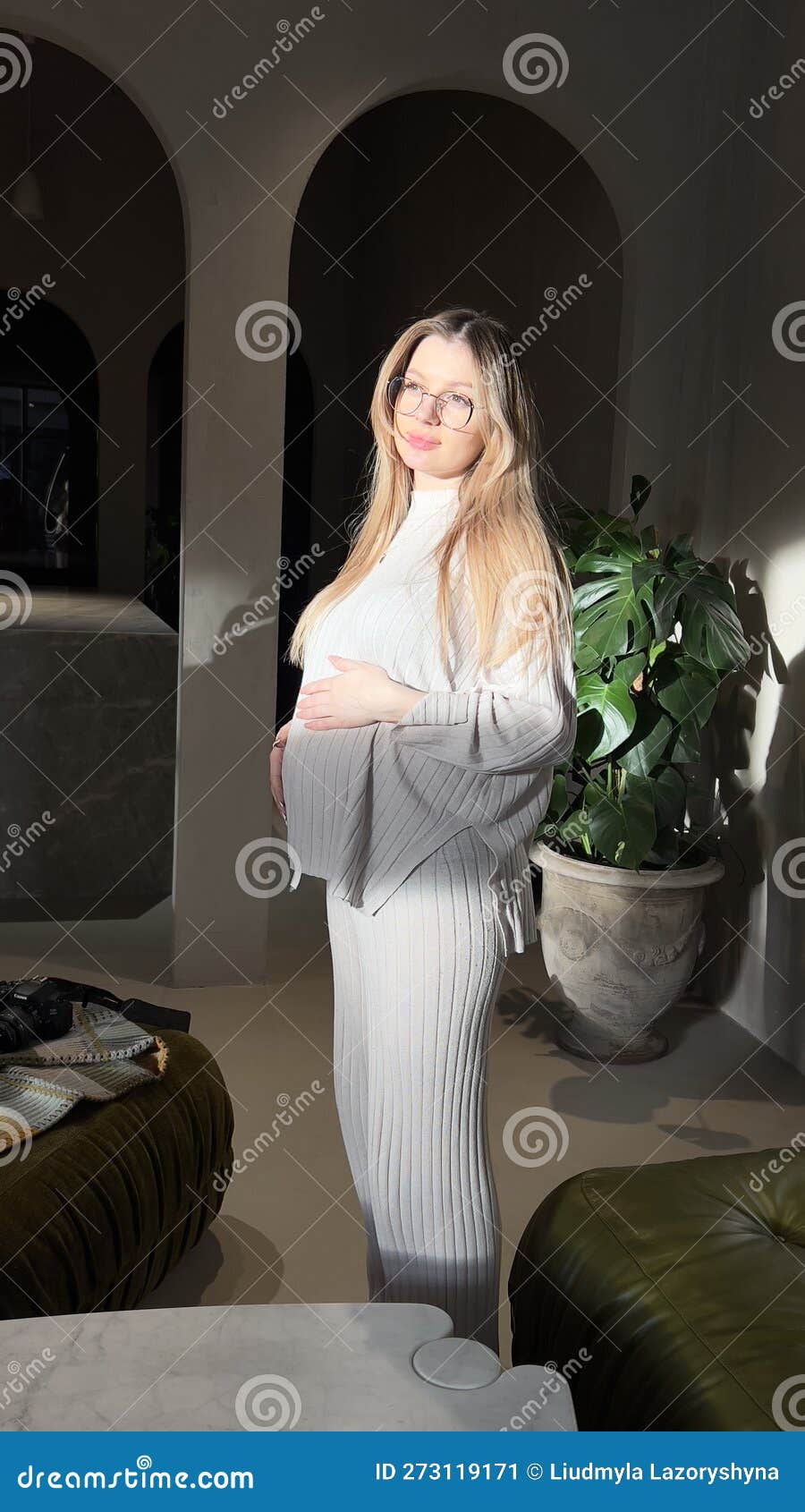 Pregnant Beautiful Woman In Glasses In A Dark Room Under Sunlight Stock