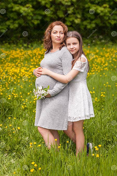 Pregnant Mother With Her Daughter Well Dressed In The Green Park Sunny