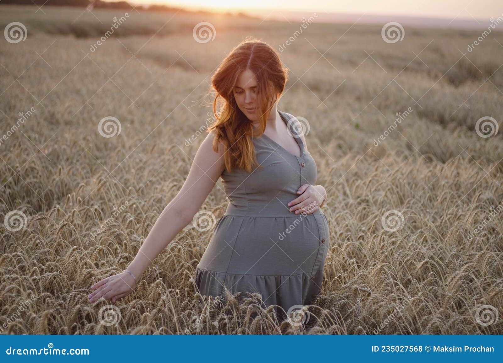 Pregnant Red Haired Young Woman Walking On Agricultural Field Stroking
