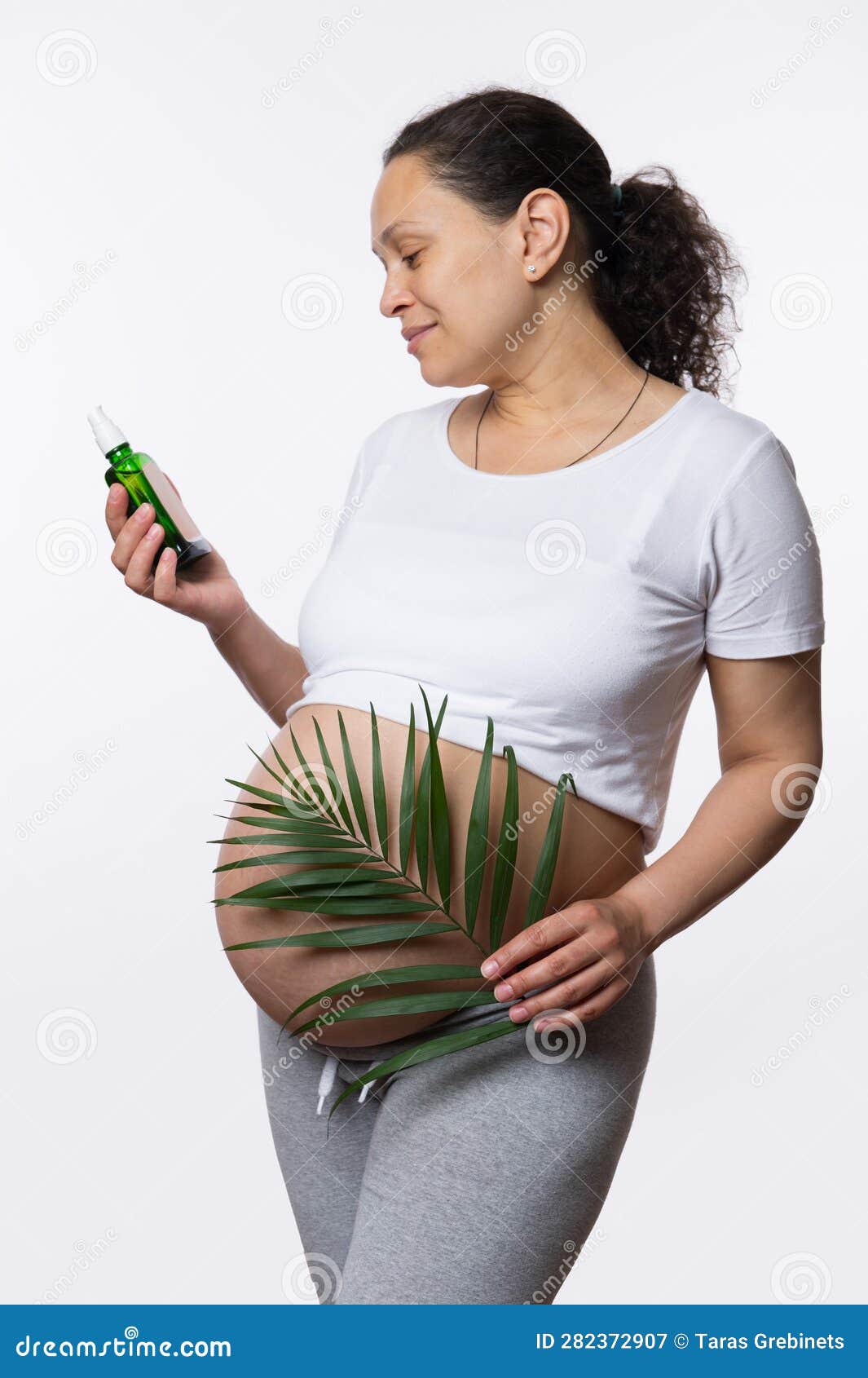 Pregnant Woman With Exotic Palm Leaf And Cosmetic Oil To Avoid Stretch