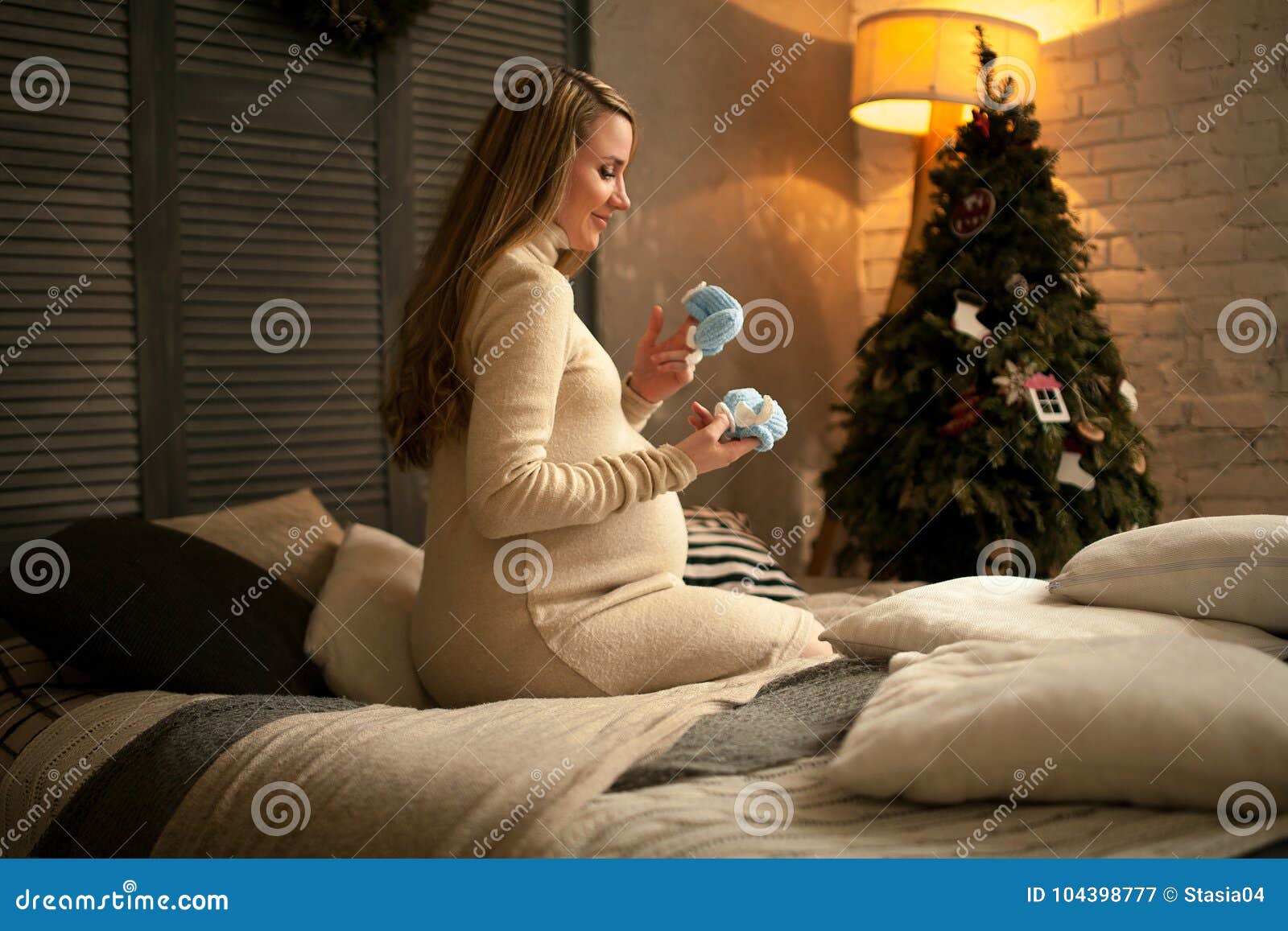 Pregnant Woman Sits before Christmas Tree and Looks at Baby`s Bo Stock ... Pregnant Woman Sits before Christmas Tree and Looks at Baby`s Bo Stock ...