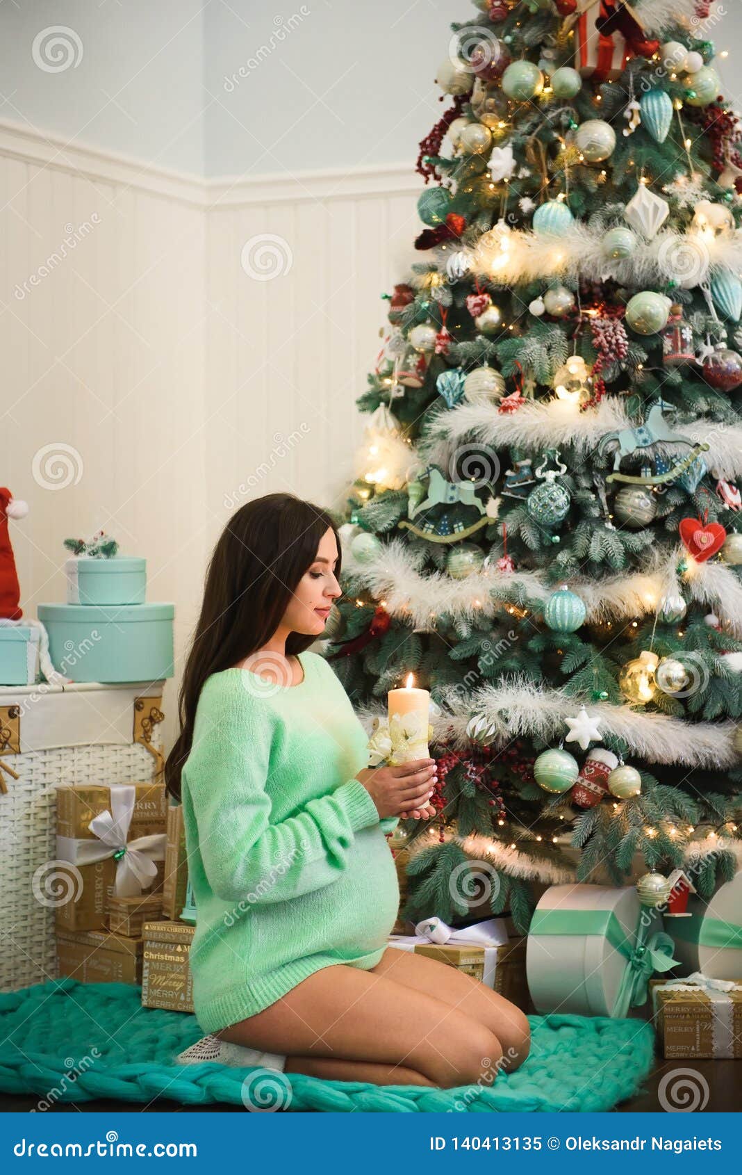 Pregnant Woman Sits Near Christmas Tree with a Candle in Her Hands ... Pregnant Woman Sits Near Christmas Tree with a Candle in Her Hands ...