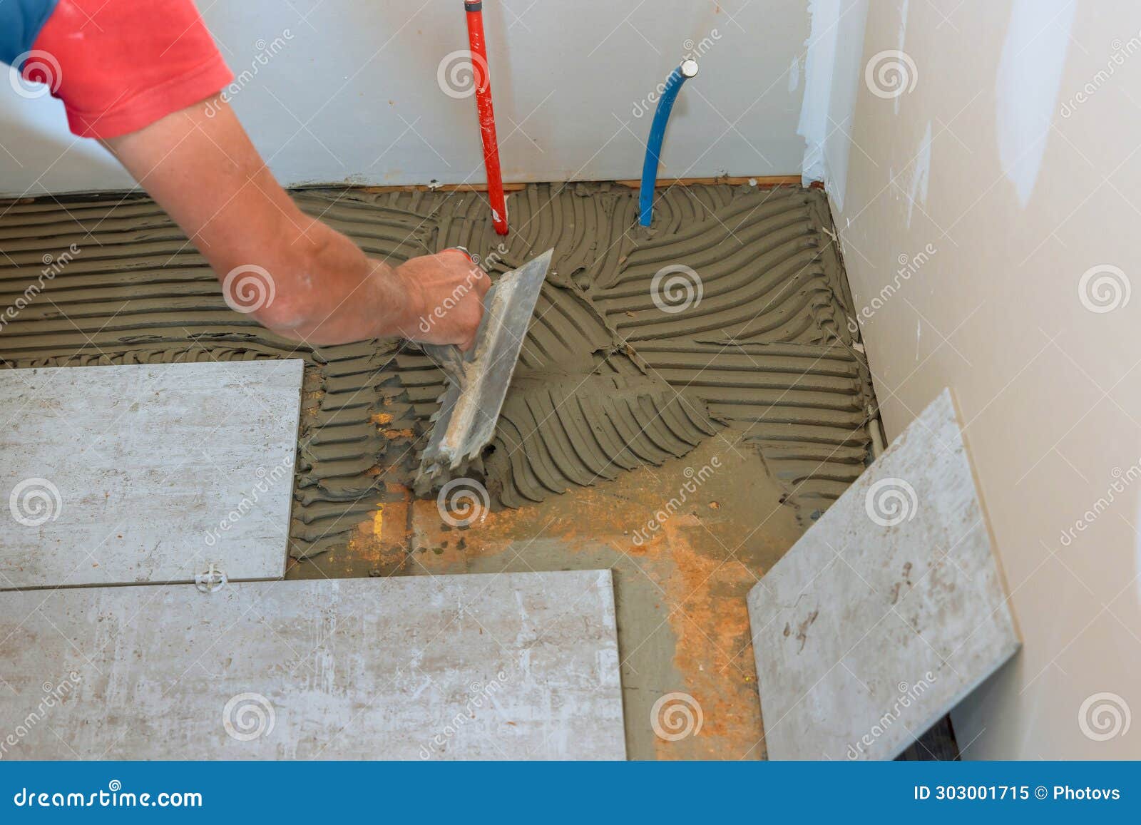 Preparing a Concrete Floor for Tiling by Troweling Adhesive Onto ...