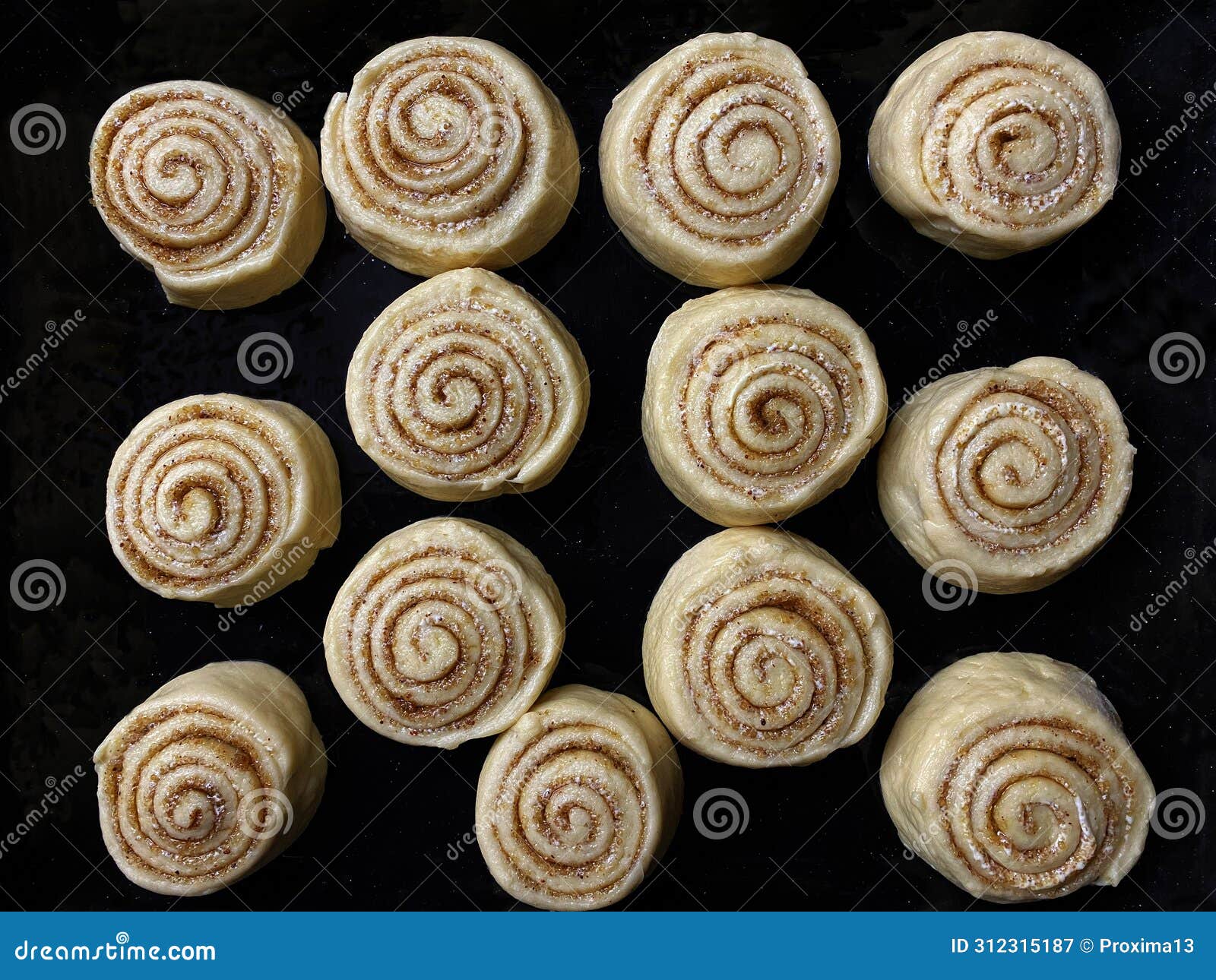Preparing Homemade Round Cinnamon Scrolls in a Rectangular Black Baking ...