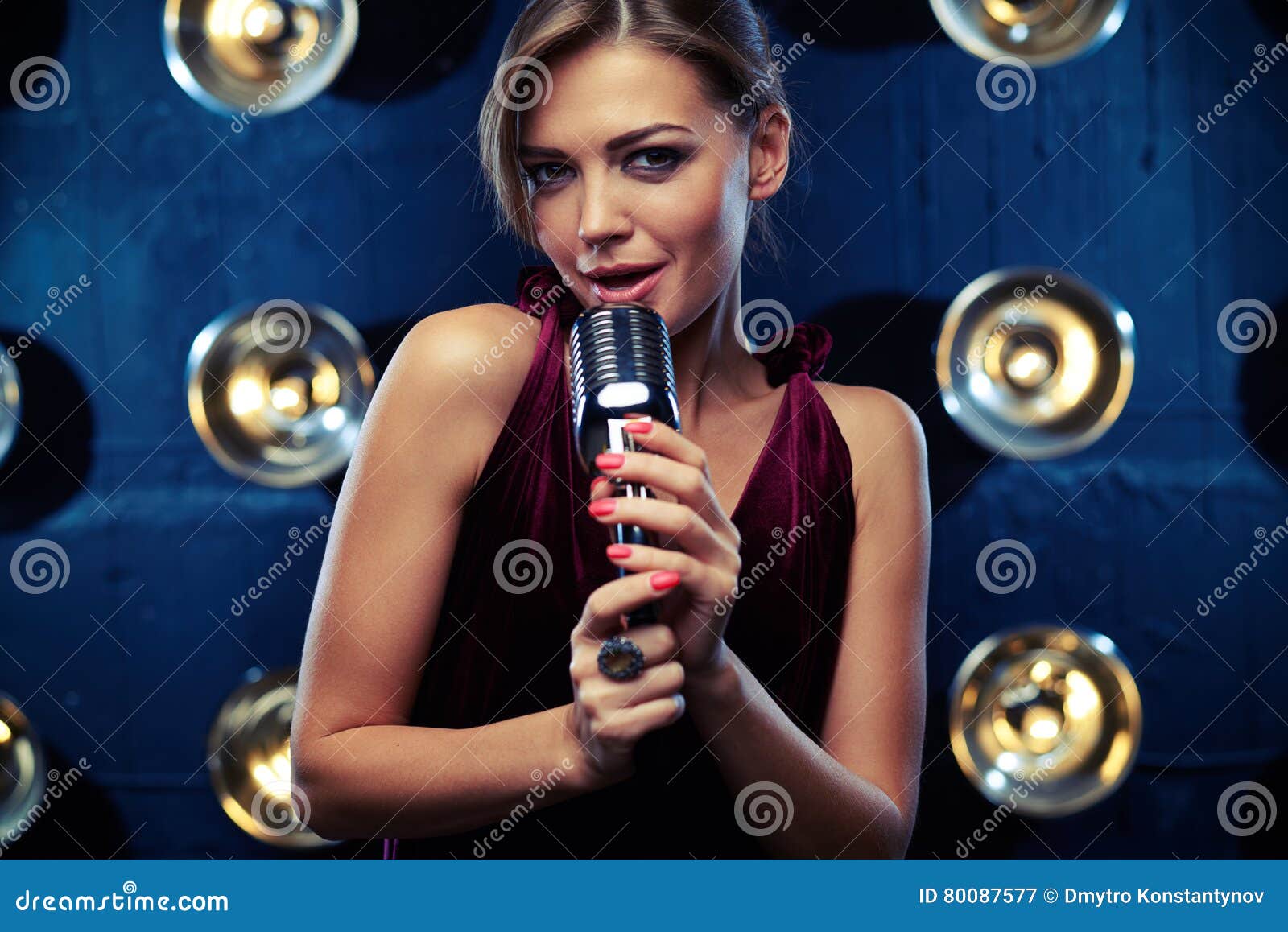 Pretty Appealing Woman Singing with a Microphone in a Studio Lighting ...