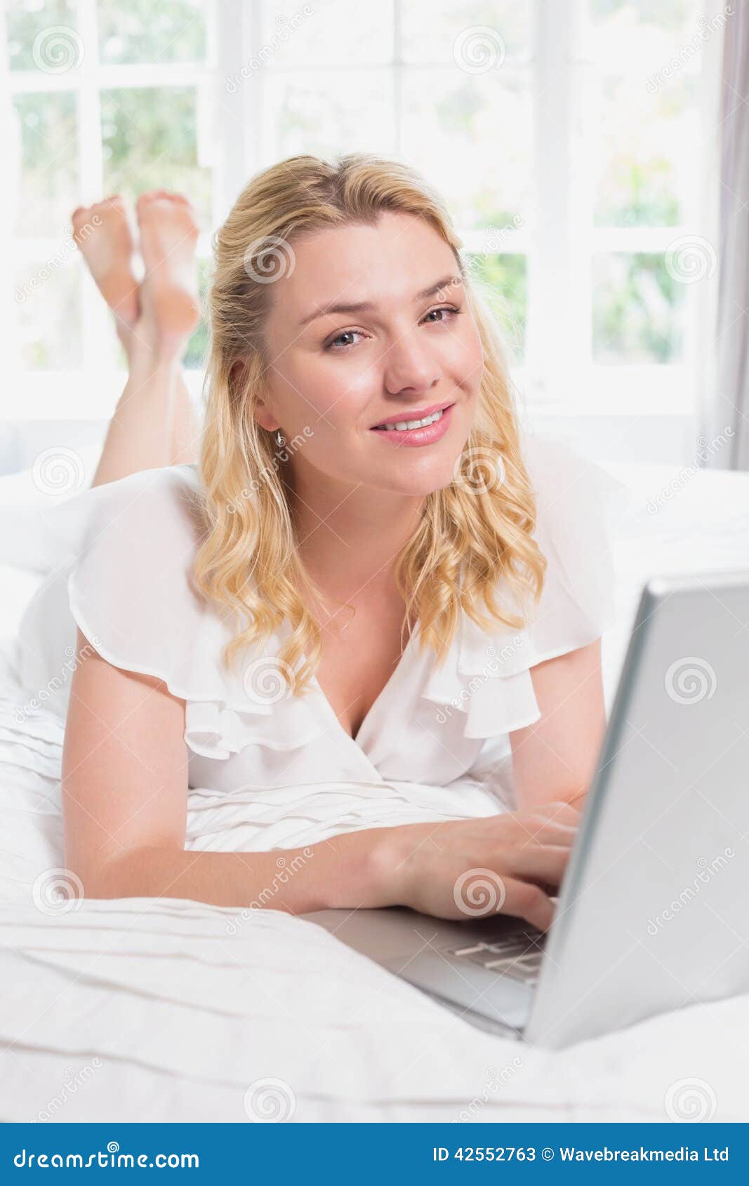 Pretty Blonde Lying on Bed Using Laptop Smiling at Camera Stock Image ...