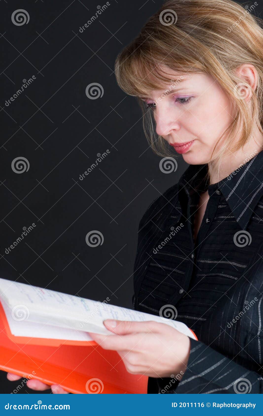 A Pretty Female Manager Reading through a Folder with a Black Ba Stock ...