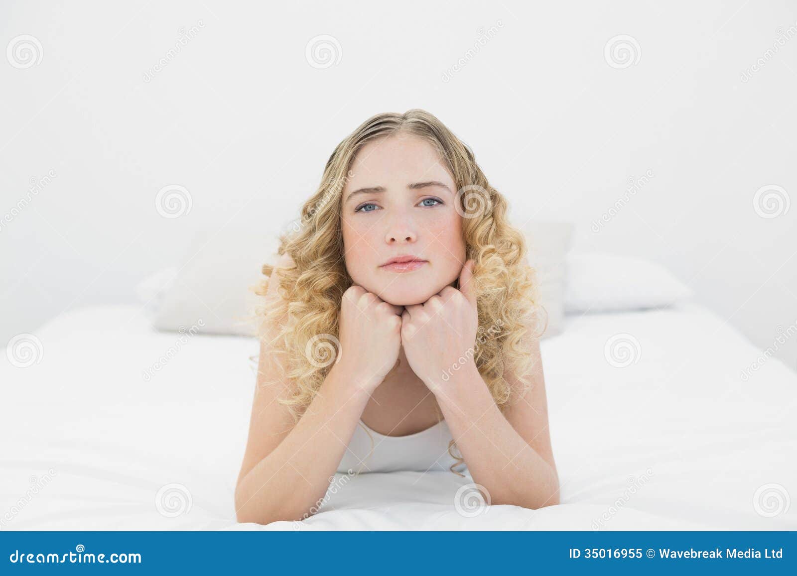 Pretty Frowning Blonde Lying on Bed Looking at Camera Stock Image ...