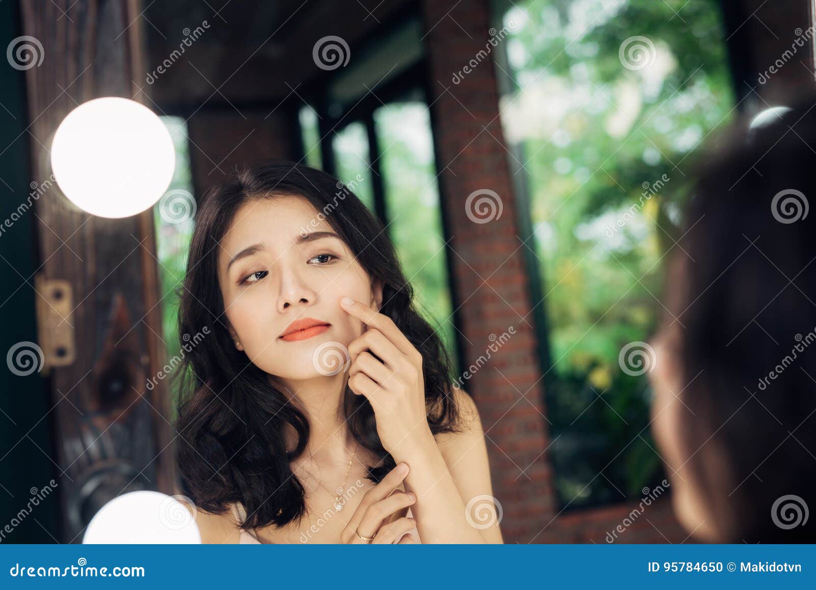 Pretty Happy Asian Woman Watching On Herself In A Big Mirror At Stock