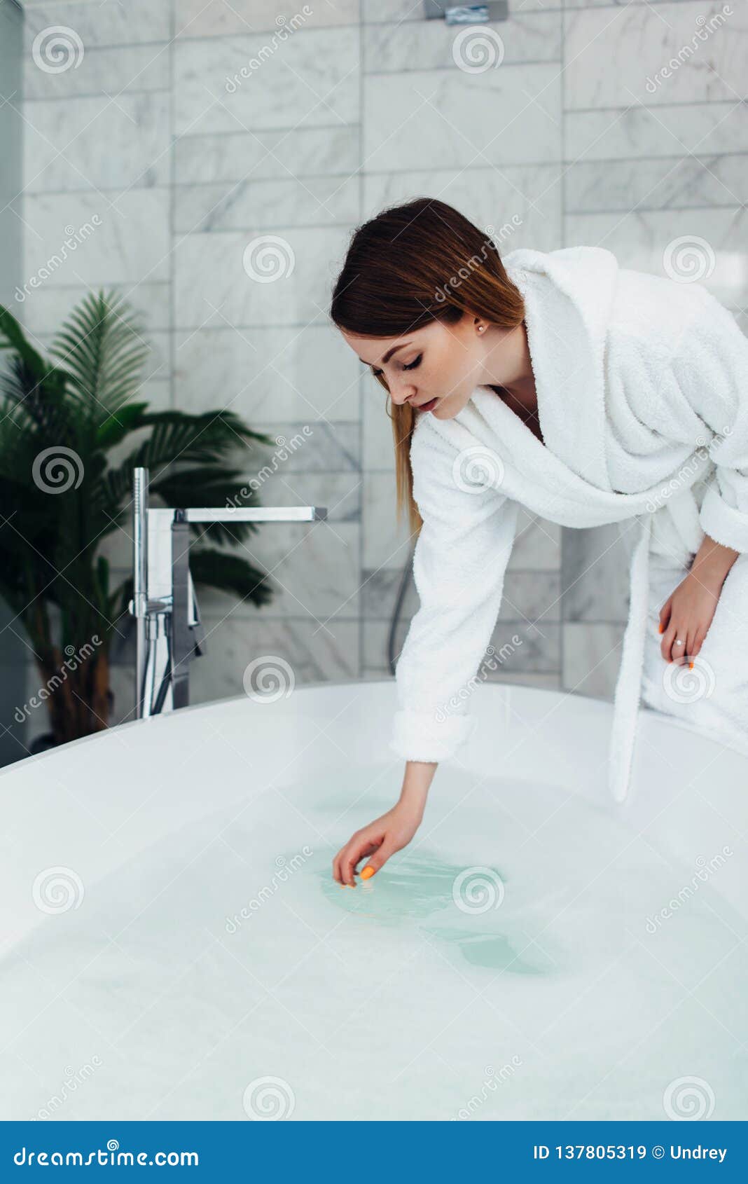 Pretty Slim Woman Wearing Bathrobe Sitting on Edge of Bathtub Filling ... Pretty Slim Woman Wearing Bathrobe Sitting on Edge of Bathtub Filling ...