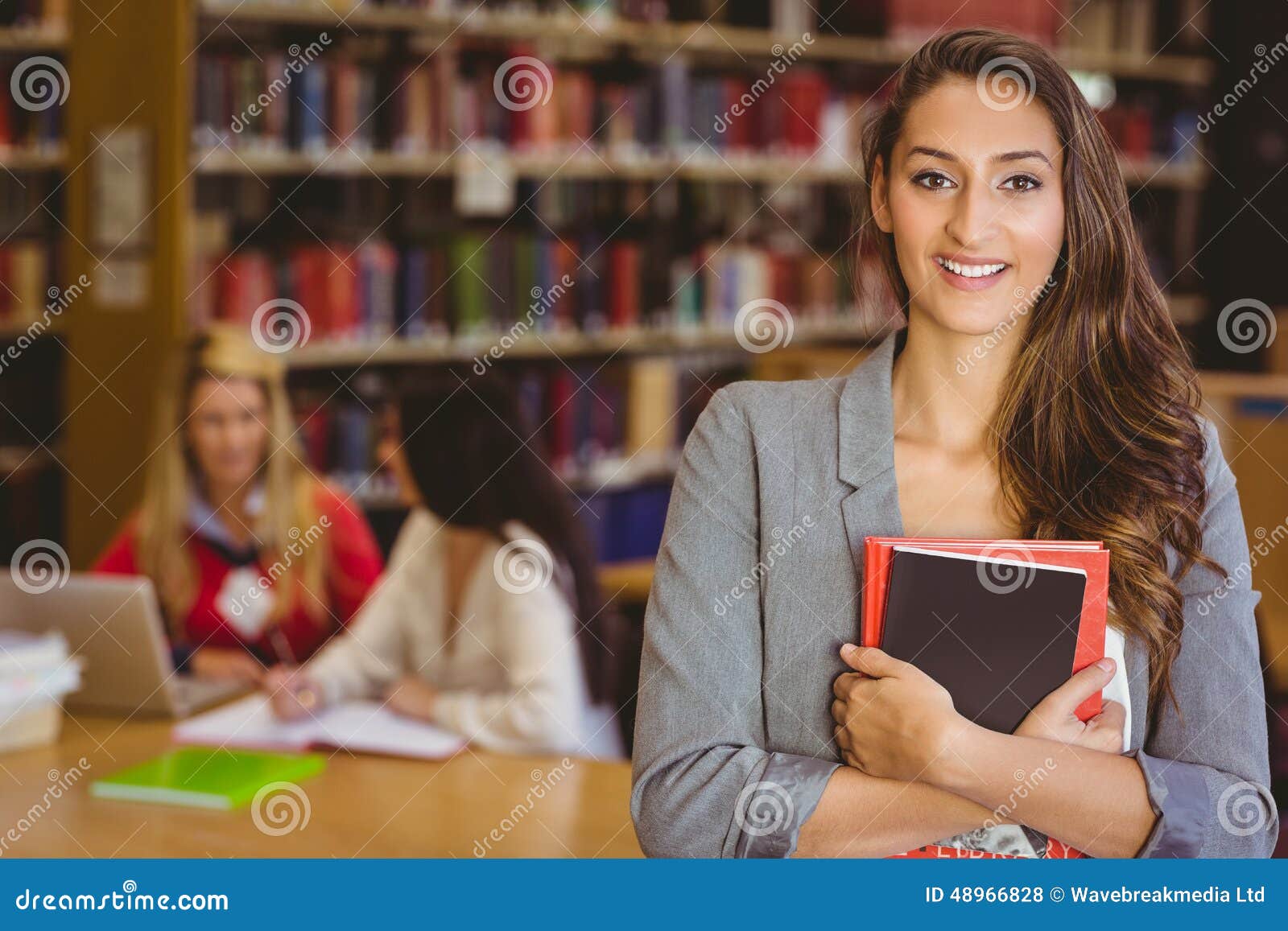 Pretty Student Holding Books with Classmates Behind Her Stock Photo ...