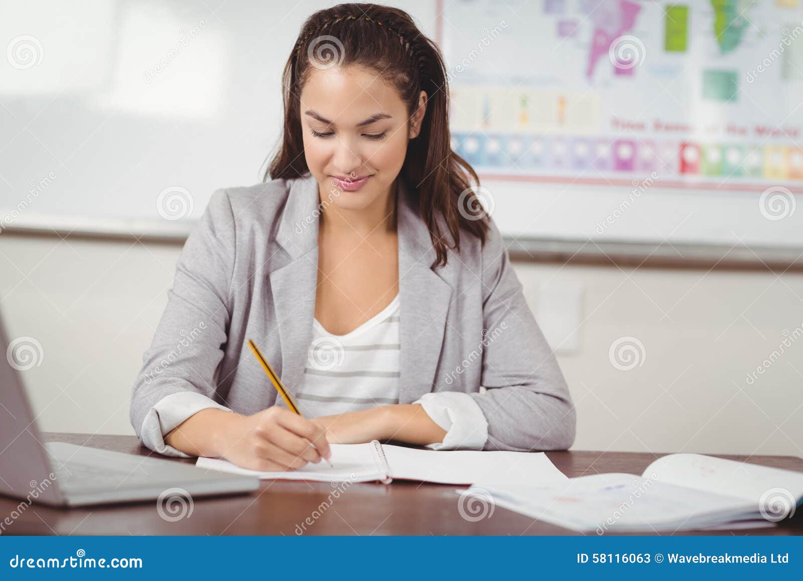 Pretty Teacher Correcting at Her Desk in a Classroom Stock Image ...