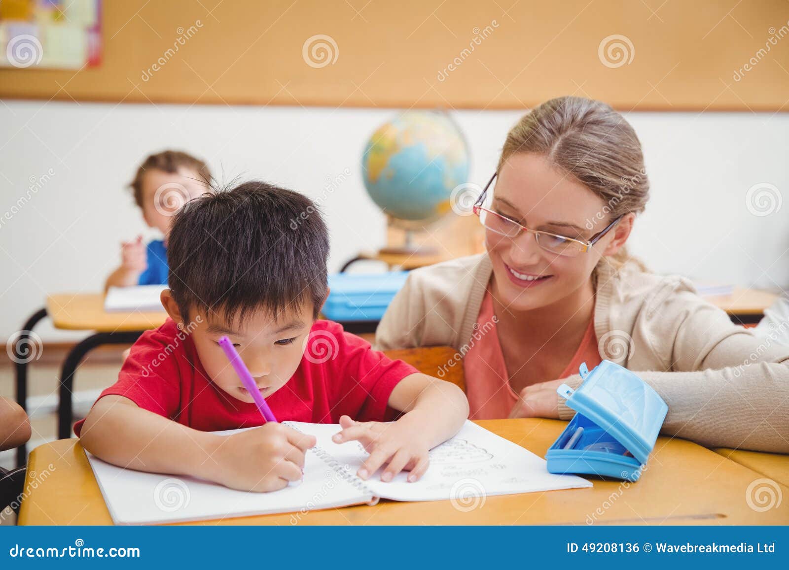 Pretty Teacher Helping Pupil in Classroom Stock Photo - Image of ...